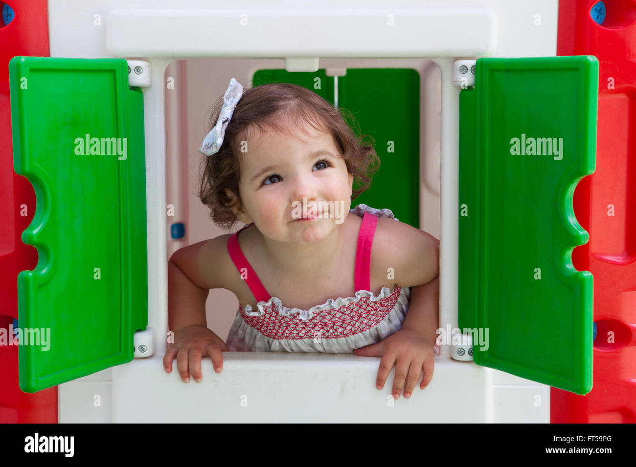 Little brown hair girl smiling through the window of kids playhouse ...