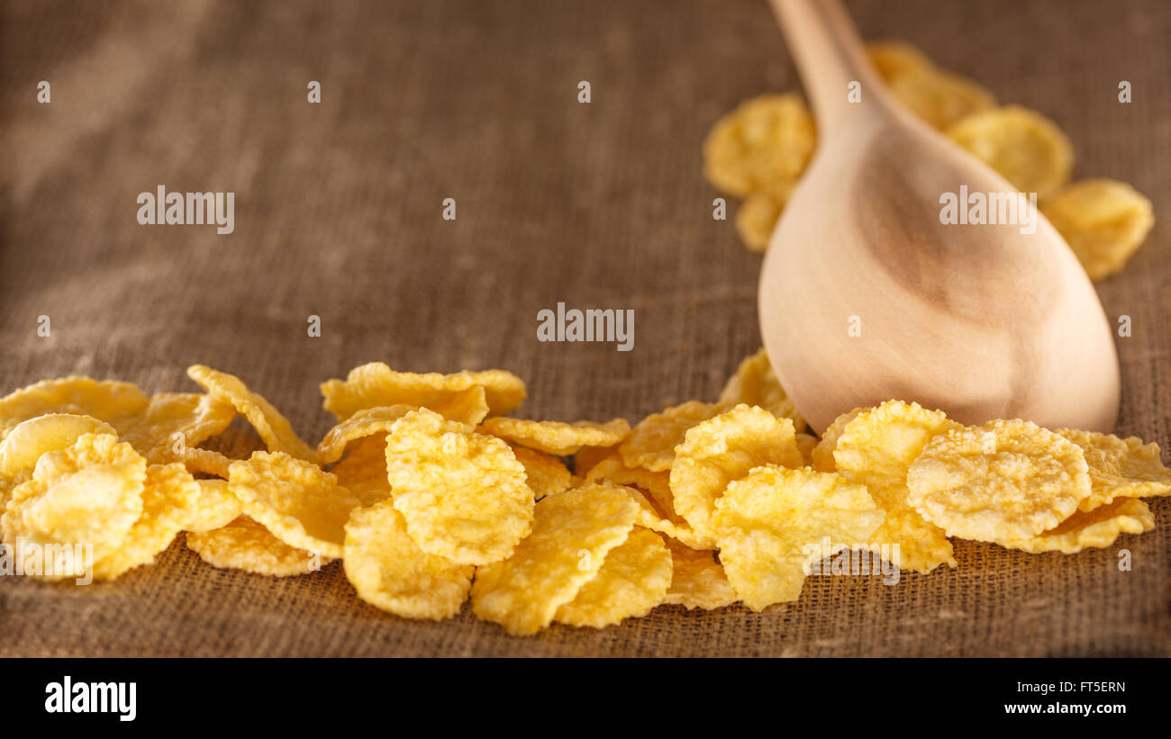Wooden spoon and corn flakes on sack background closeup Stock Photo - Alamy