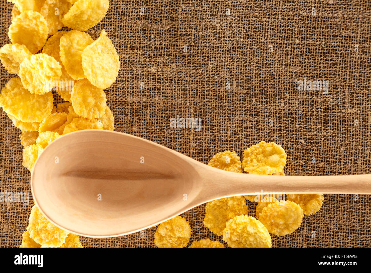 Wooden spoon and corn flakes on sack background closeup Stock Photo - Alamy