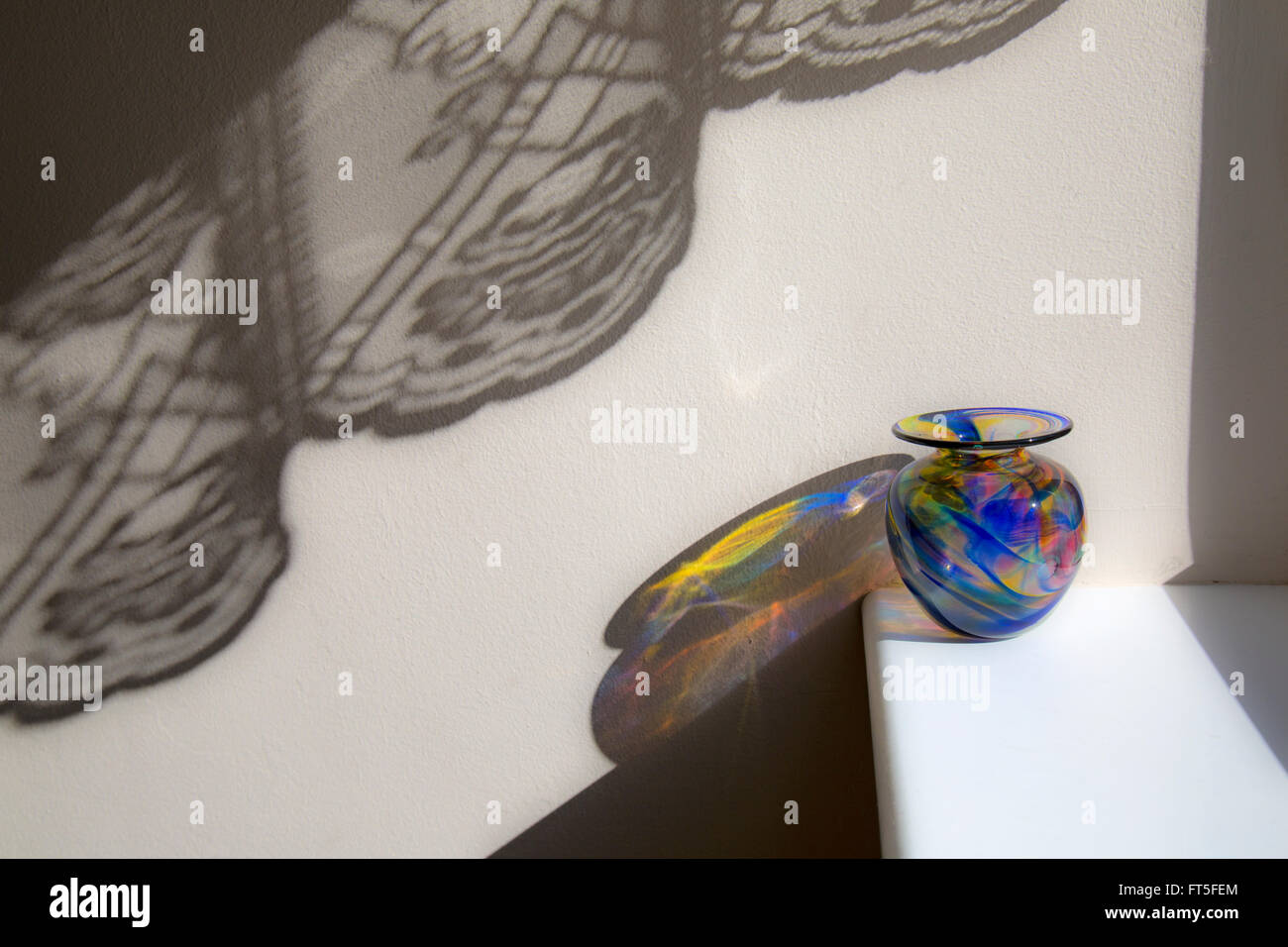 Sunlight streaming through a window casting colours from a glass vase ...