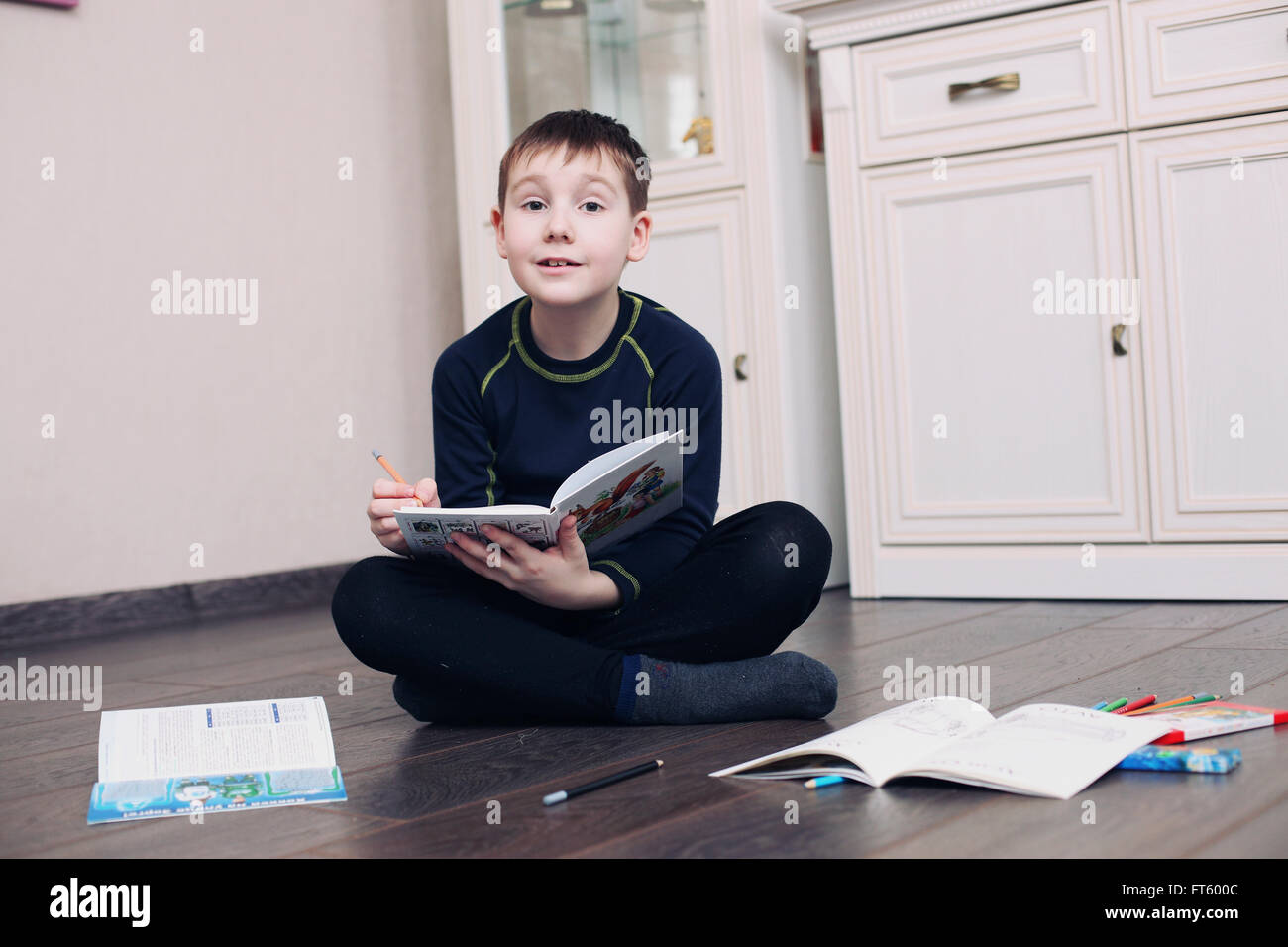 the child does homework at home on a floor with book Stock Photo - Alamy