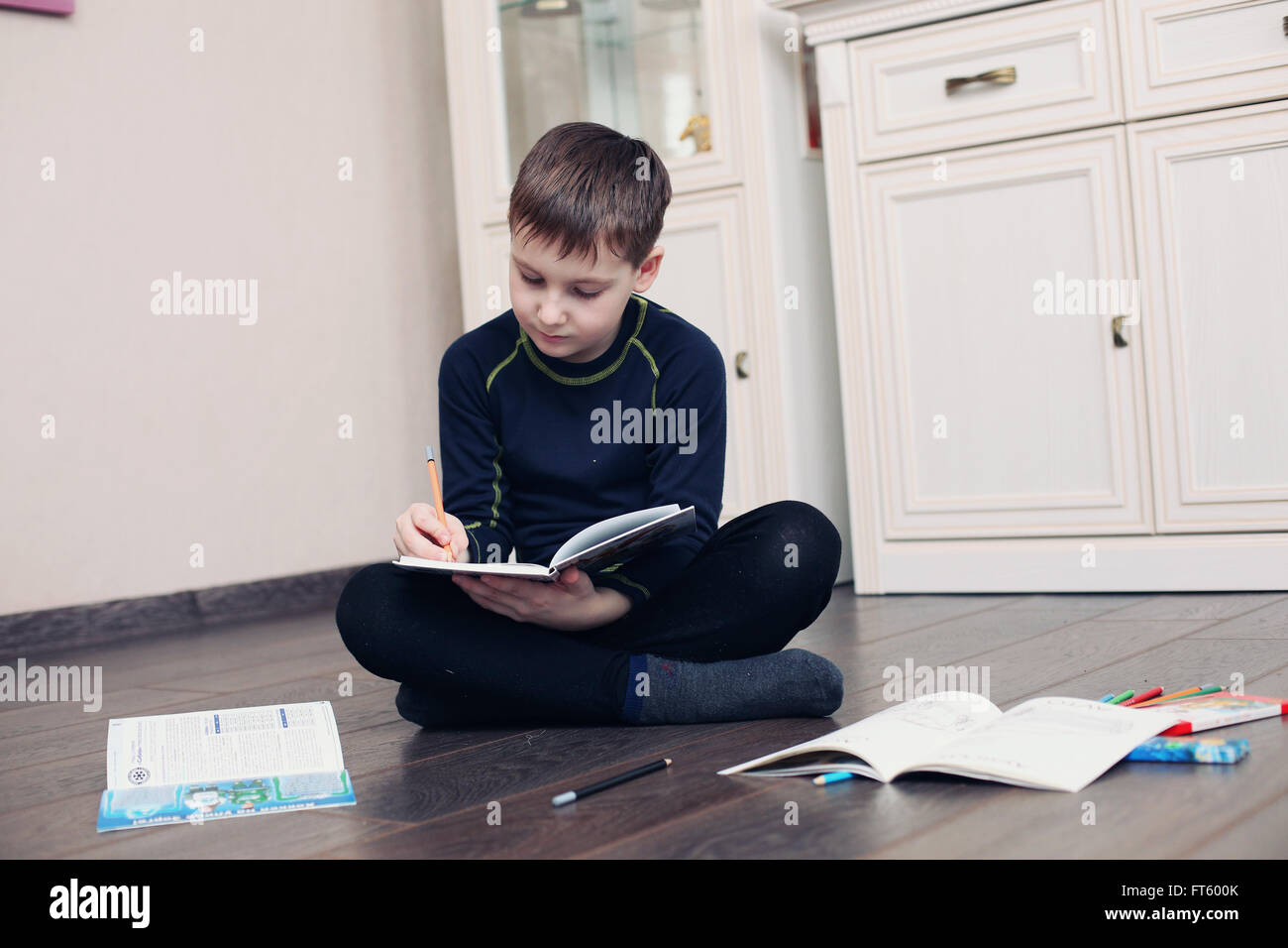 the child does homework at home on a floor with book Stock Photo - Alamy