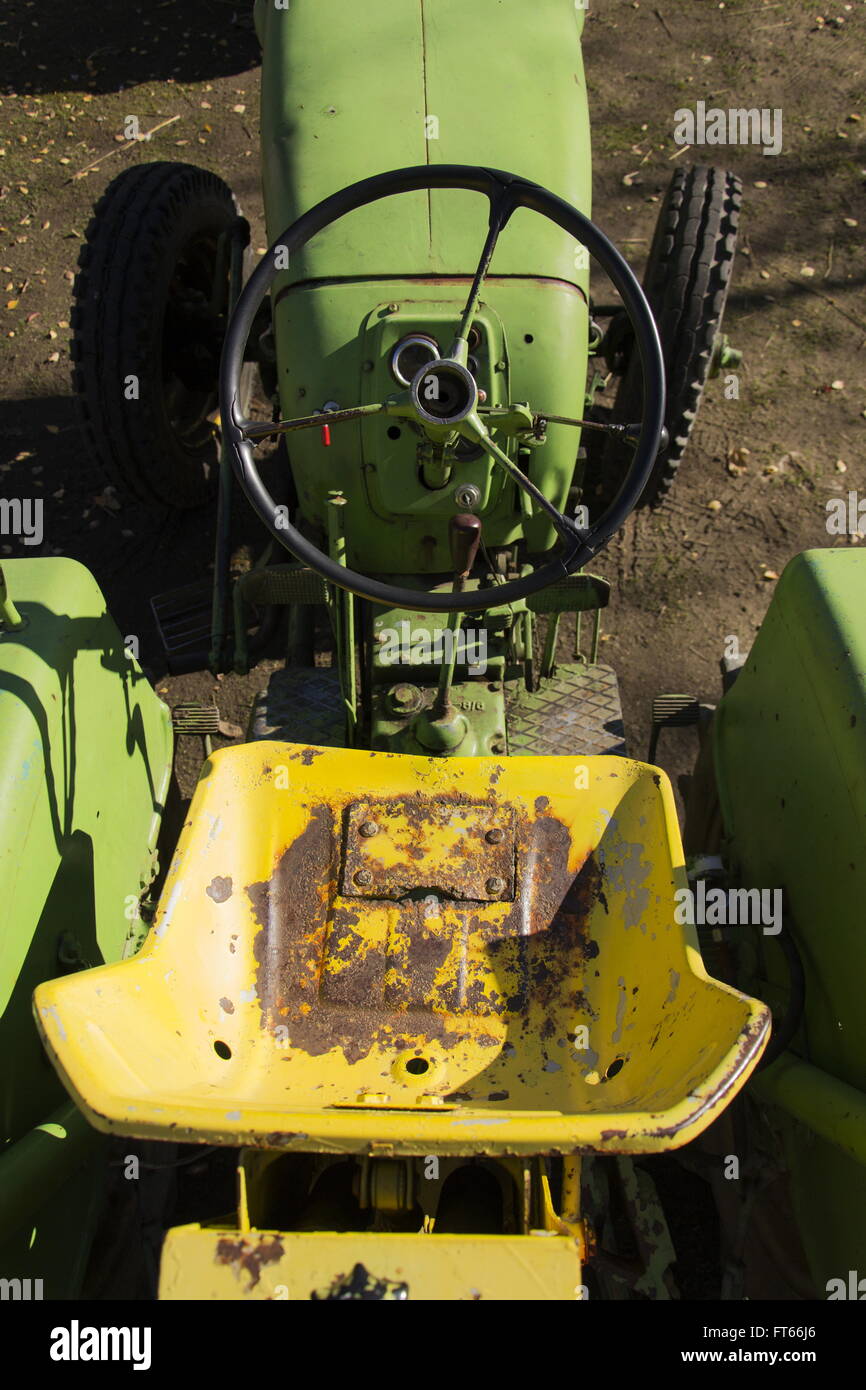 Old green vintage tractor stands on farm yard on a sunny autumn day ...