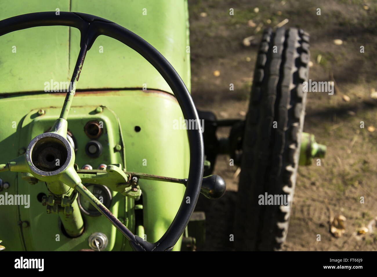Old green vintage tractor stands on farm yard on a sunny autumn day ...