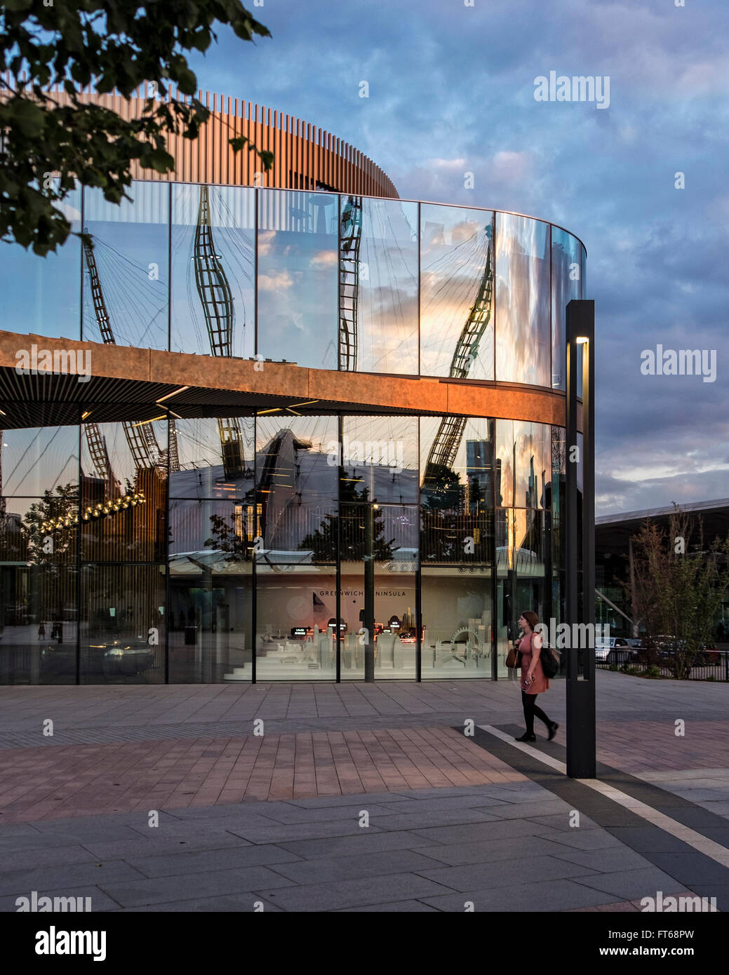 Young woman walking past modern restaurant building with reflections of ...