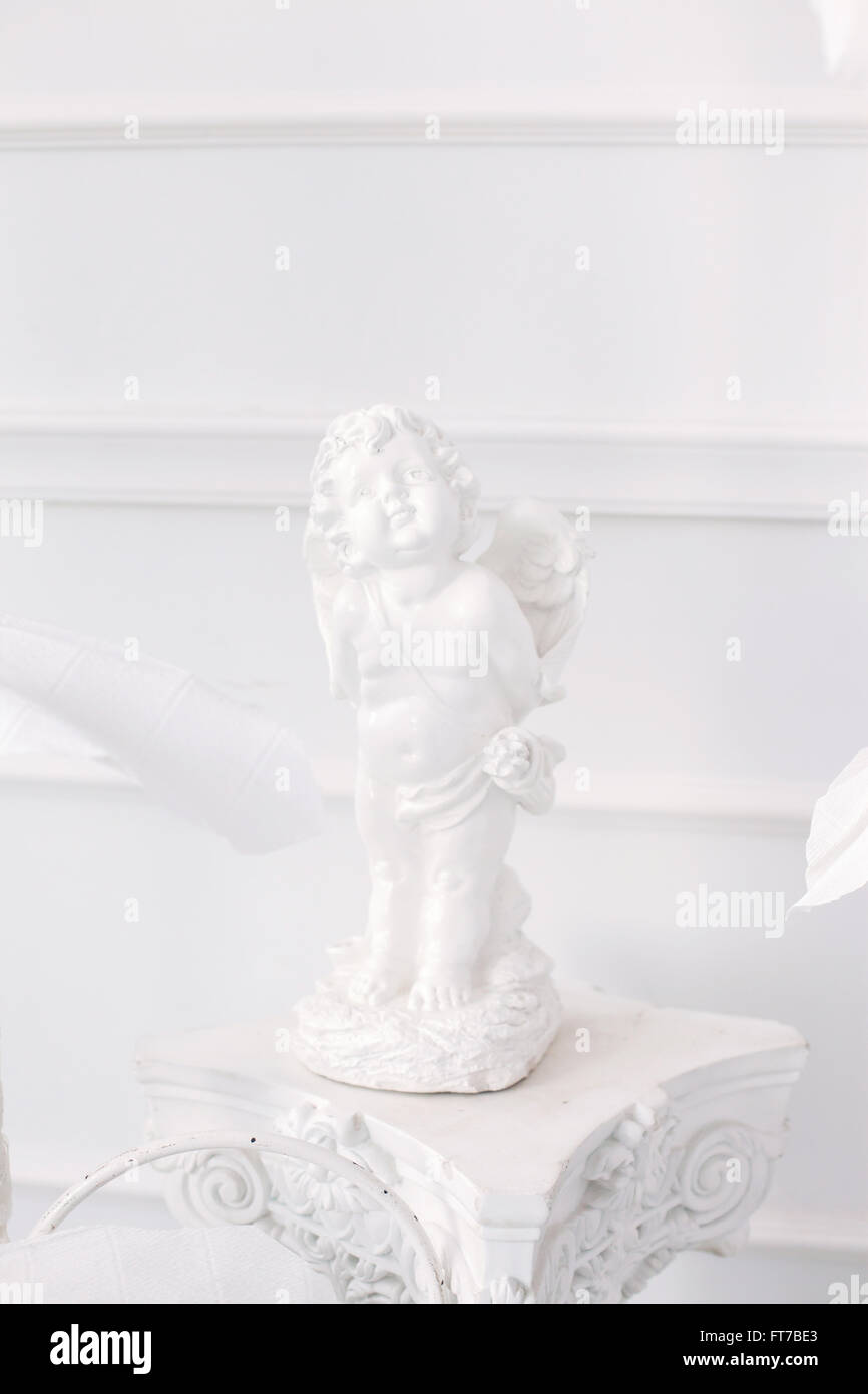 A little miniature statue of a white angel with wings in bright room ...