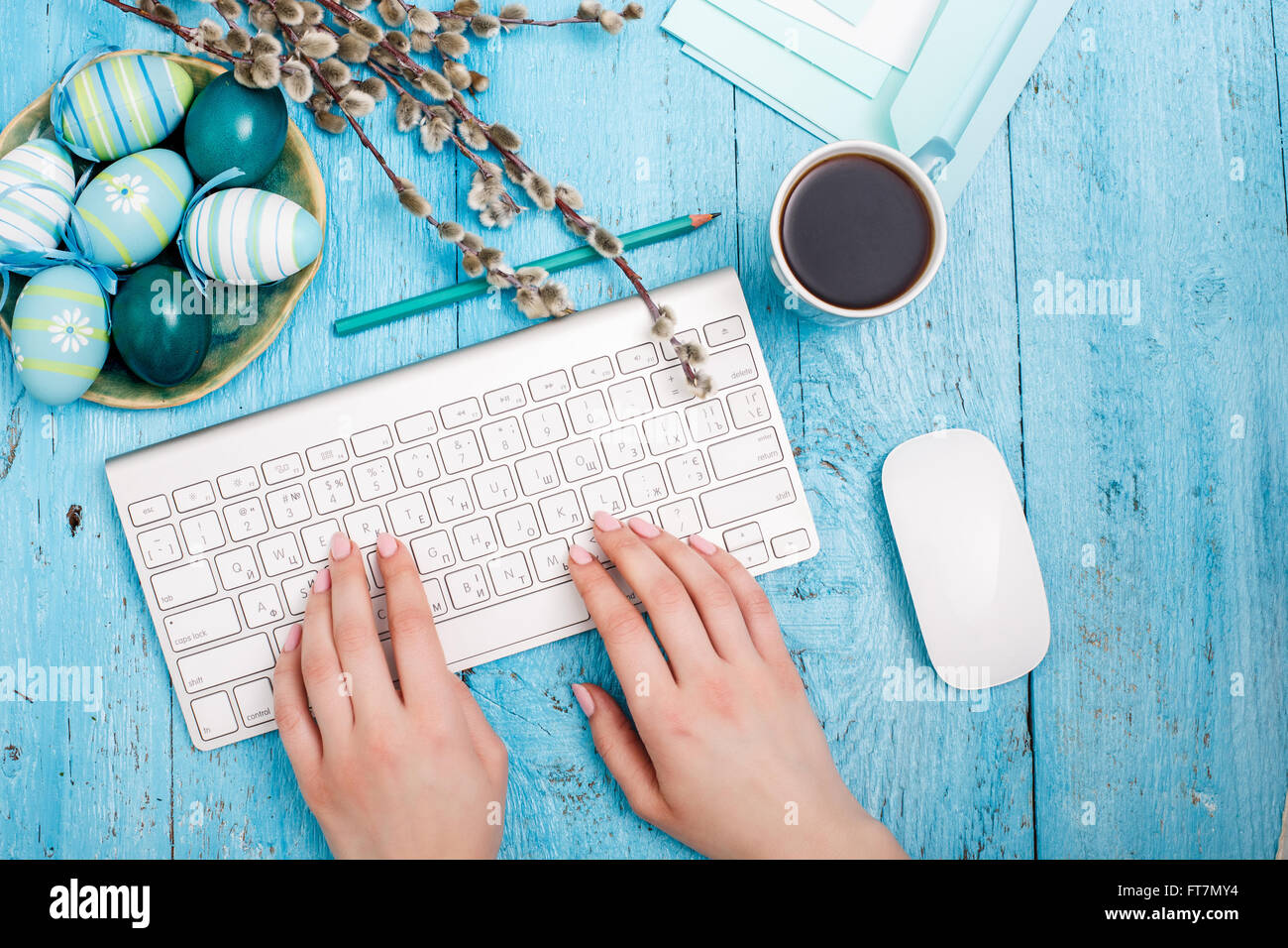 Easter in the office workplace on blue wooden table. The female hand on ...