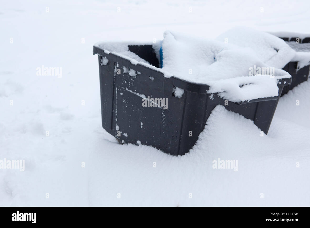 Household recycling boxes sitting outside a house in a deep layer of ...