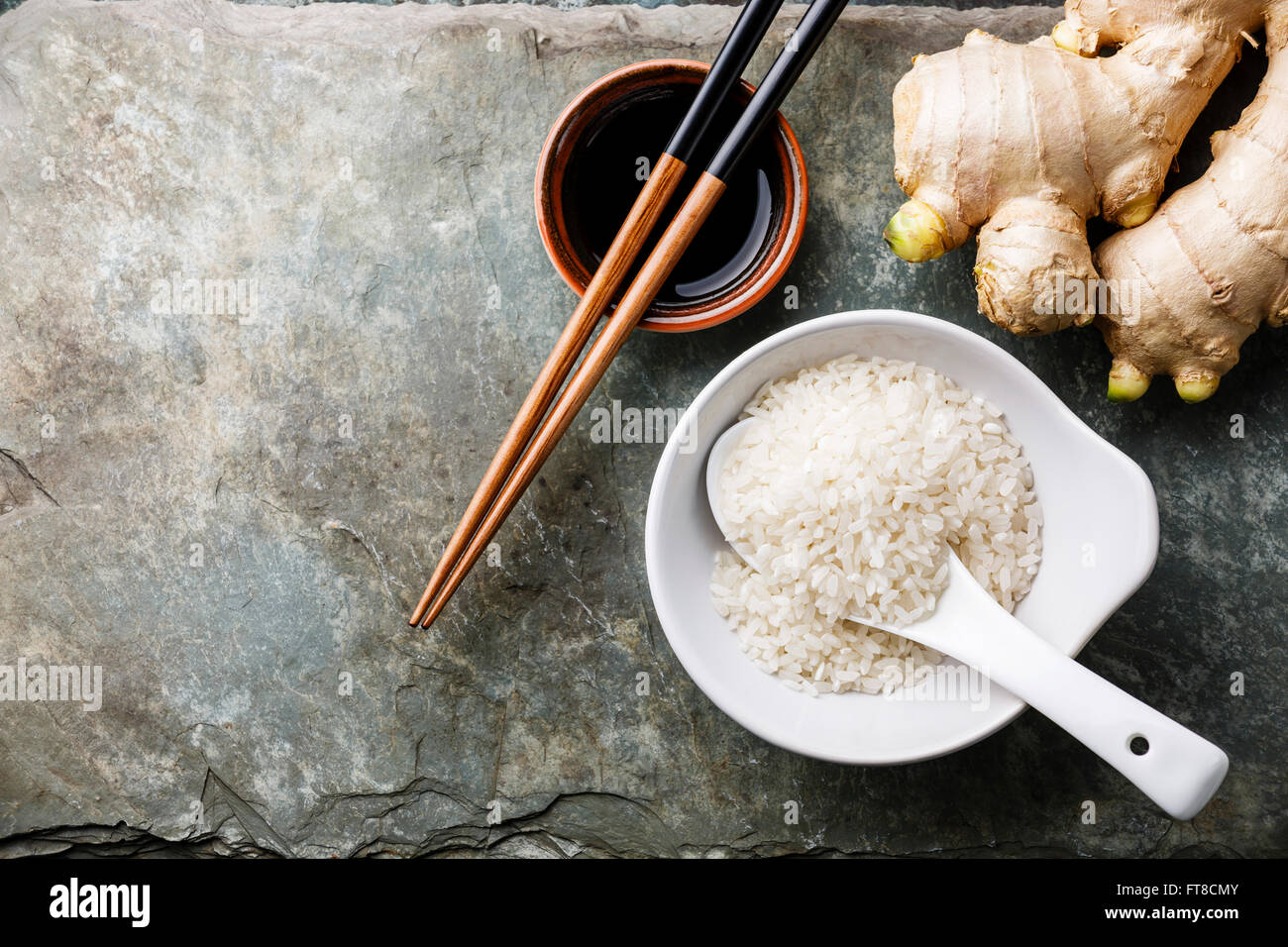 Raw white rice, fresh ginger root, soy sauce and sushi chopsticks on ...