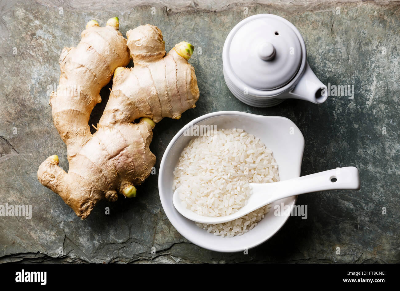 Raw white rice, fresh ginger root and soy sauce on gray stone slate ...