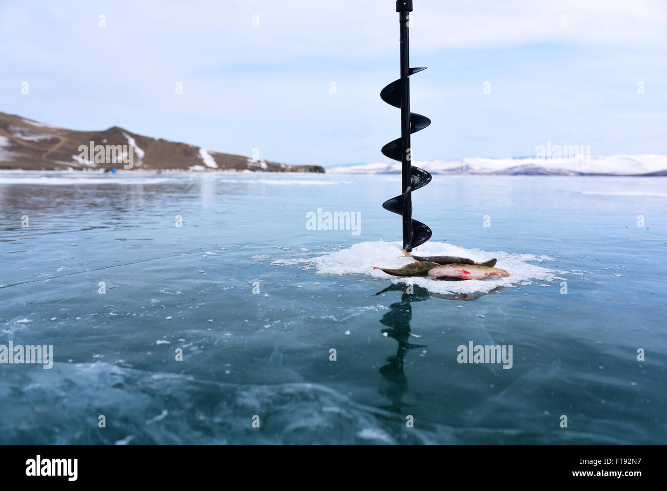 Winter fishing in the middle of frozen lake ice Stock Photo - Alamy