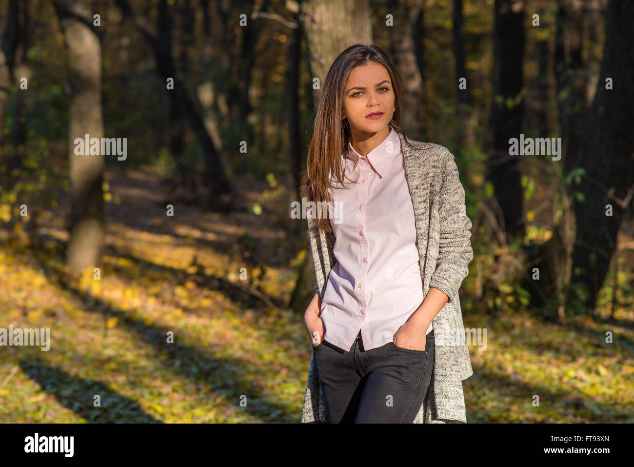A pretty teenager girl is posing in an autumn oak forest at afternoon ...