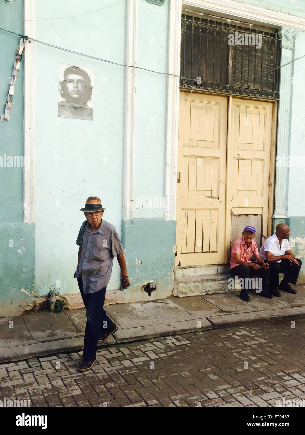 An old man walks under a portrait of Che Guevara in the street in Old ...