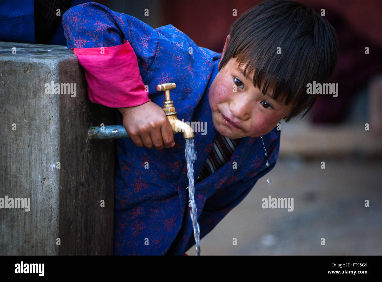 A young Bhutanese girl drinking water direct from a tap at Gangte in ...