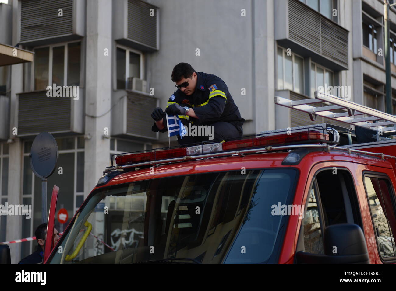 Athens, Greece. 25th Mar, 2016. A Greek fireman is placing Greek flag ...