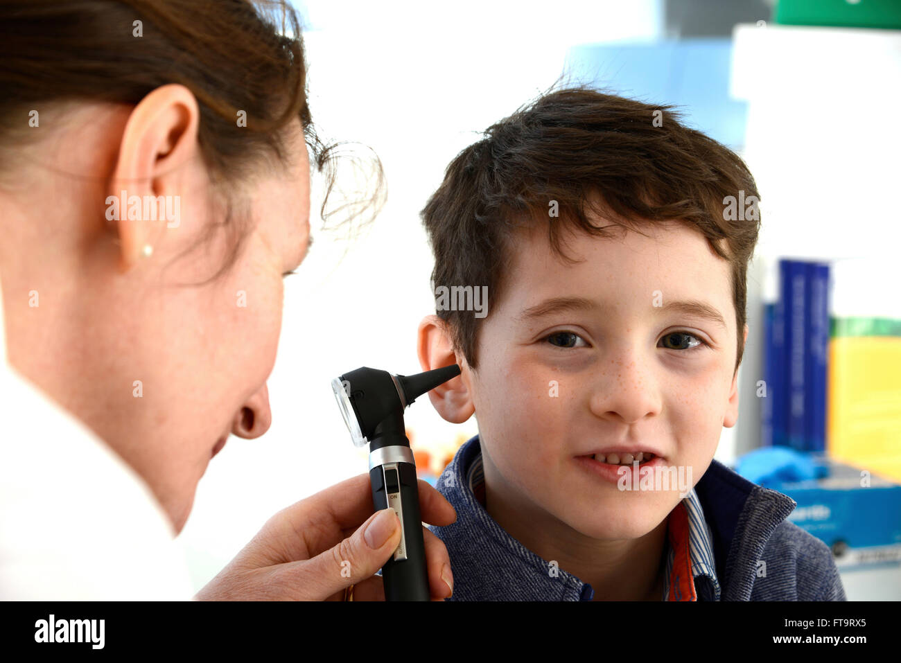 MODEL RELEASED. Paediatrician using an otoscope to examine a young boy ...
