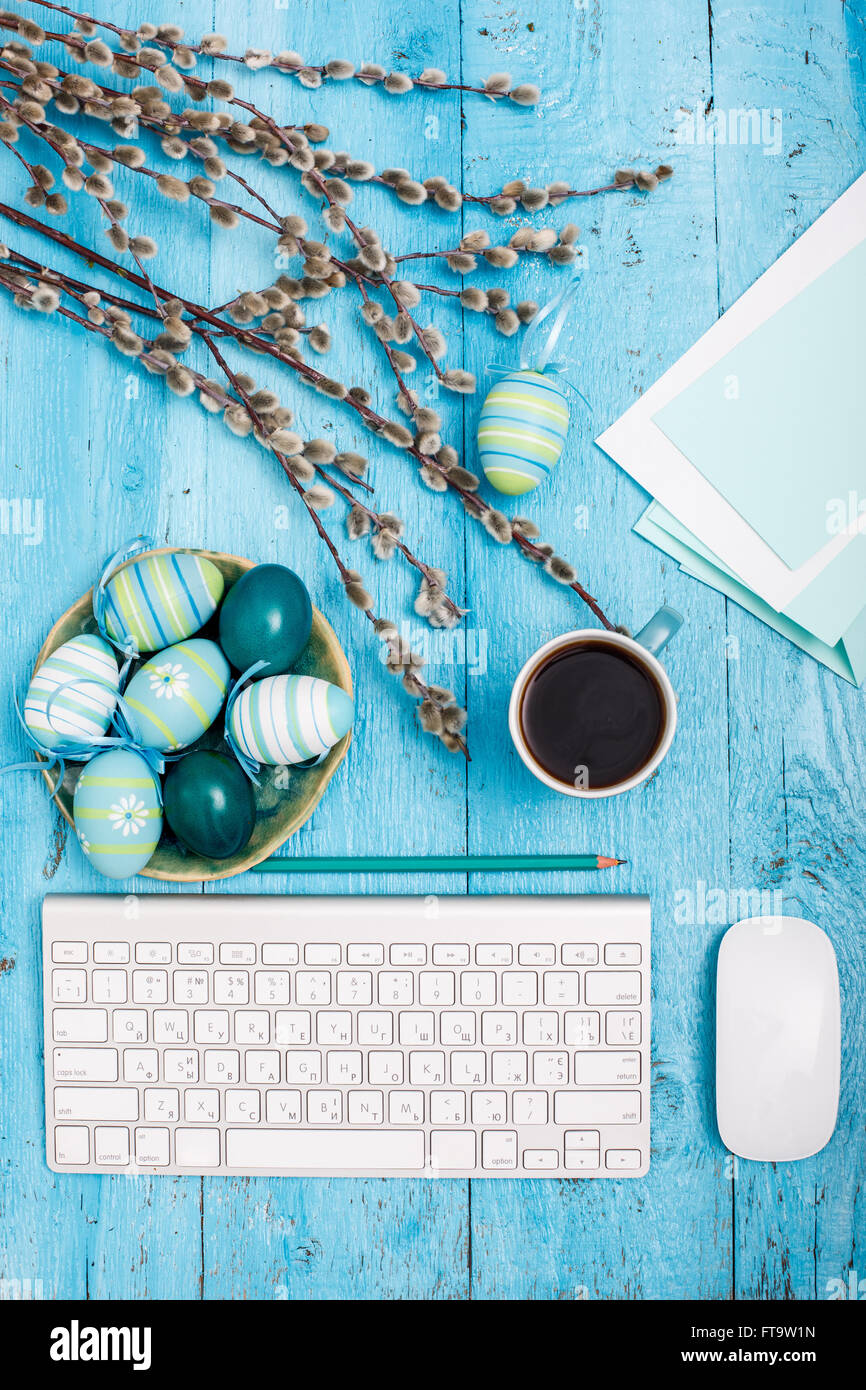 Easter in the office workplace on blue wooden table. The computer ...