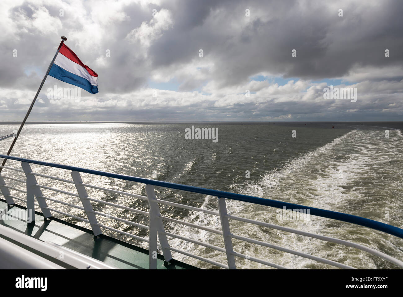 Wadden Sea with Dutch flag and wake as seen from the ferry Stock Photo ...