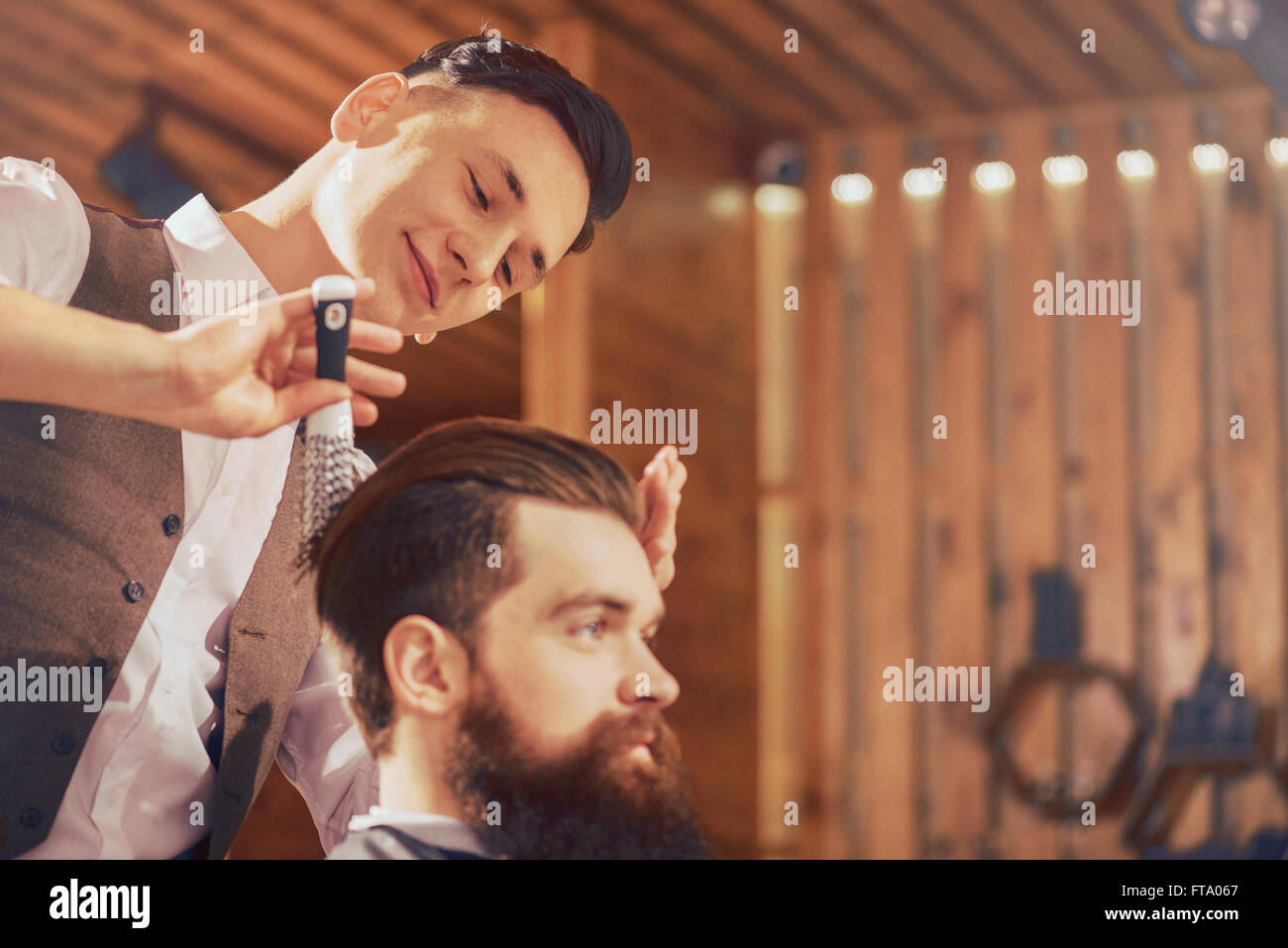 Professional barber styling hair of the client Stock Photo - Alamy