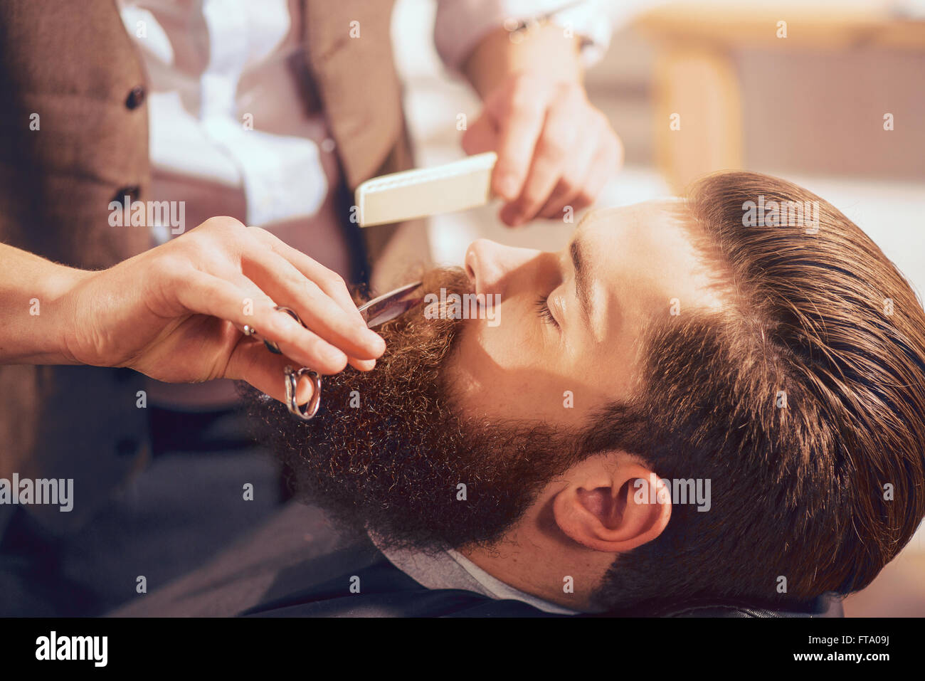 Professional barber cutting beard of handsome man Stock Photo - Alamy