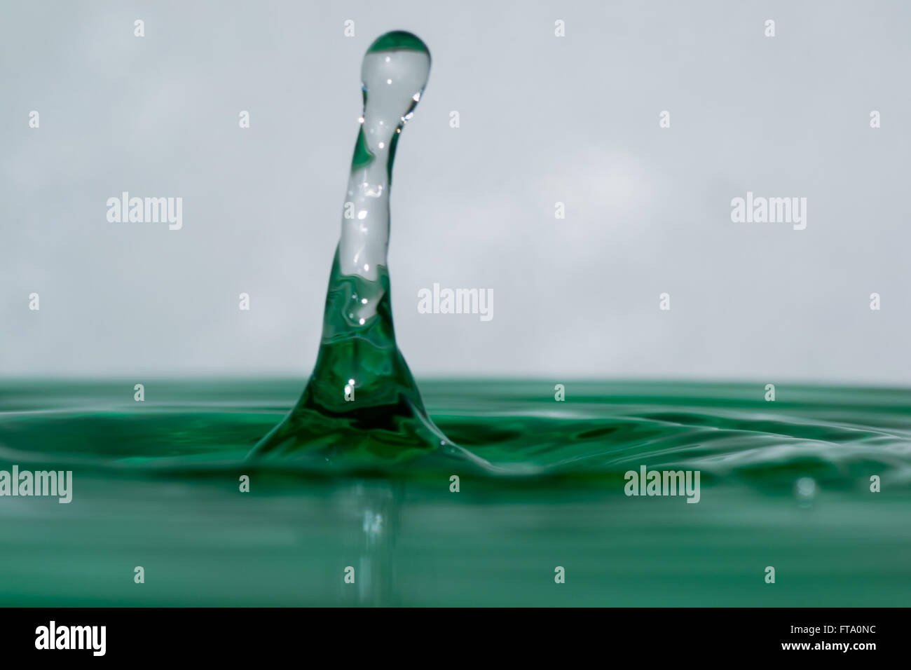 a drop of water falls and creates a splash Stock Photo - Alamy