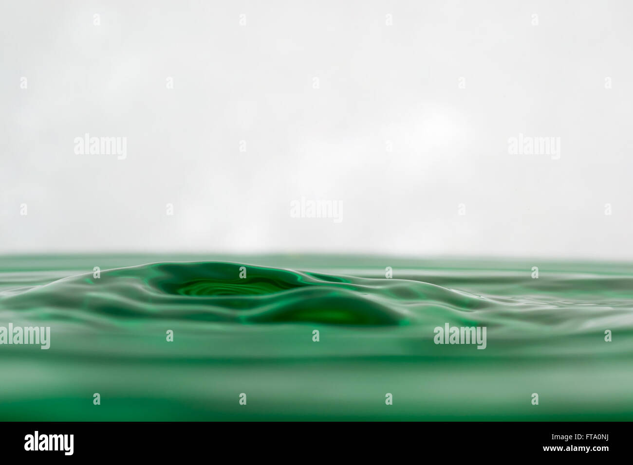 a drop of water falls and creates a splash Stock Photo - Alamy