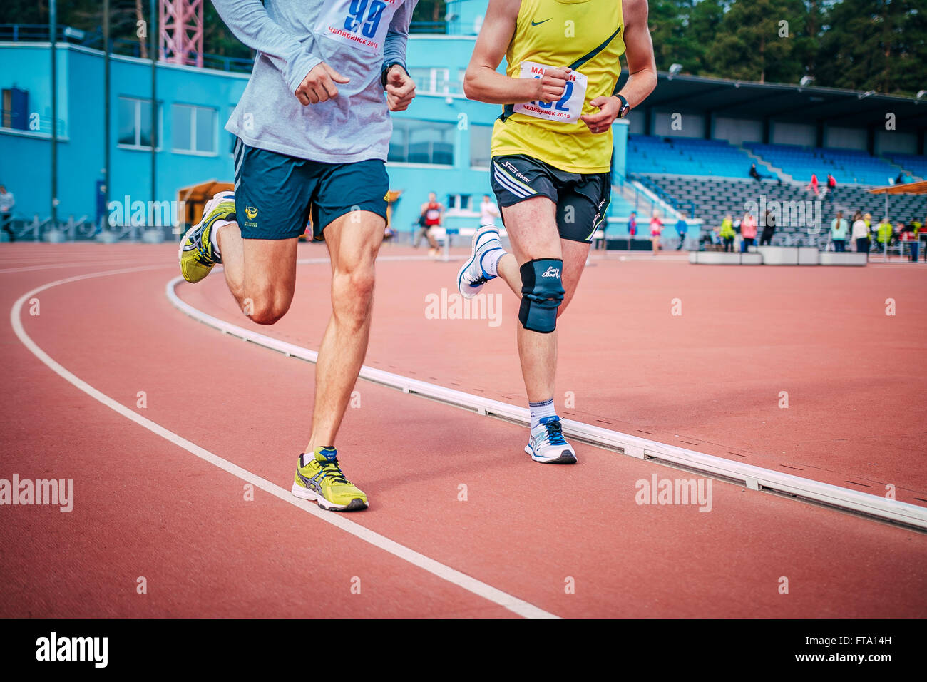 two athletes running on the track stadium during Chelyabinsk marathon ...