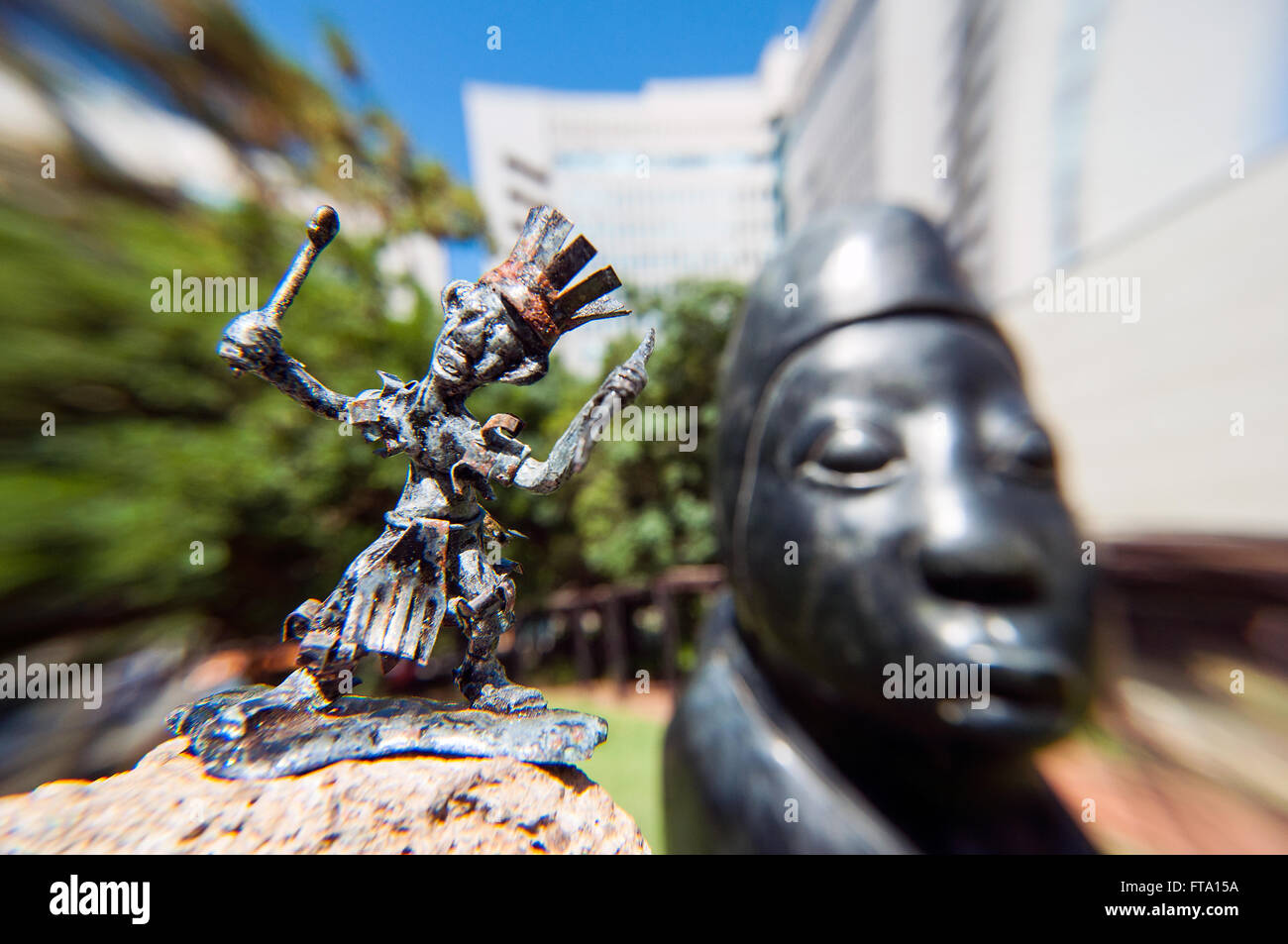 Miniature figure of Shona warrior in front of Shona-inspired sculpture ...