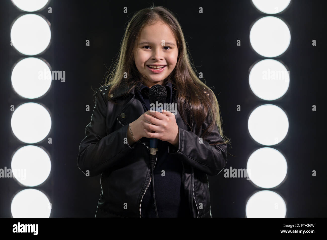 Smiling young rockstar girl holding microphone Stock Photo - Alamy