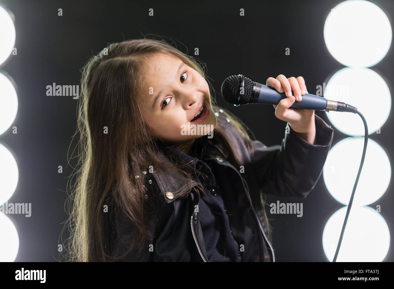 Young rockstar girl on in stage with lights behind her Stock Photo - Alamy