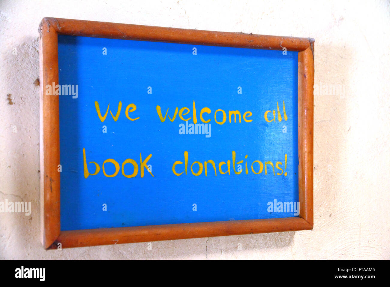 A handmade wooden and painted sign stating "We Welcome All Book ...