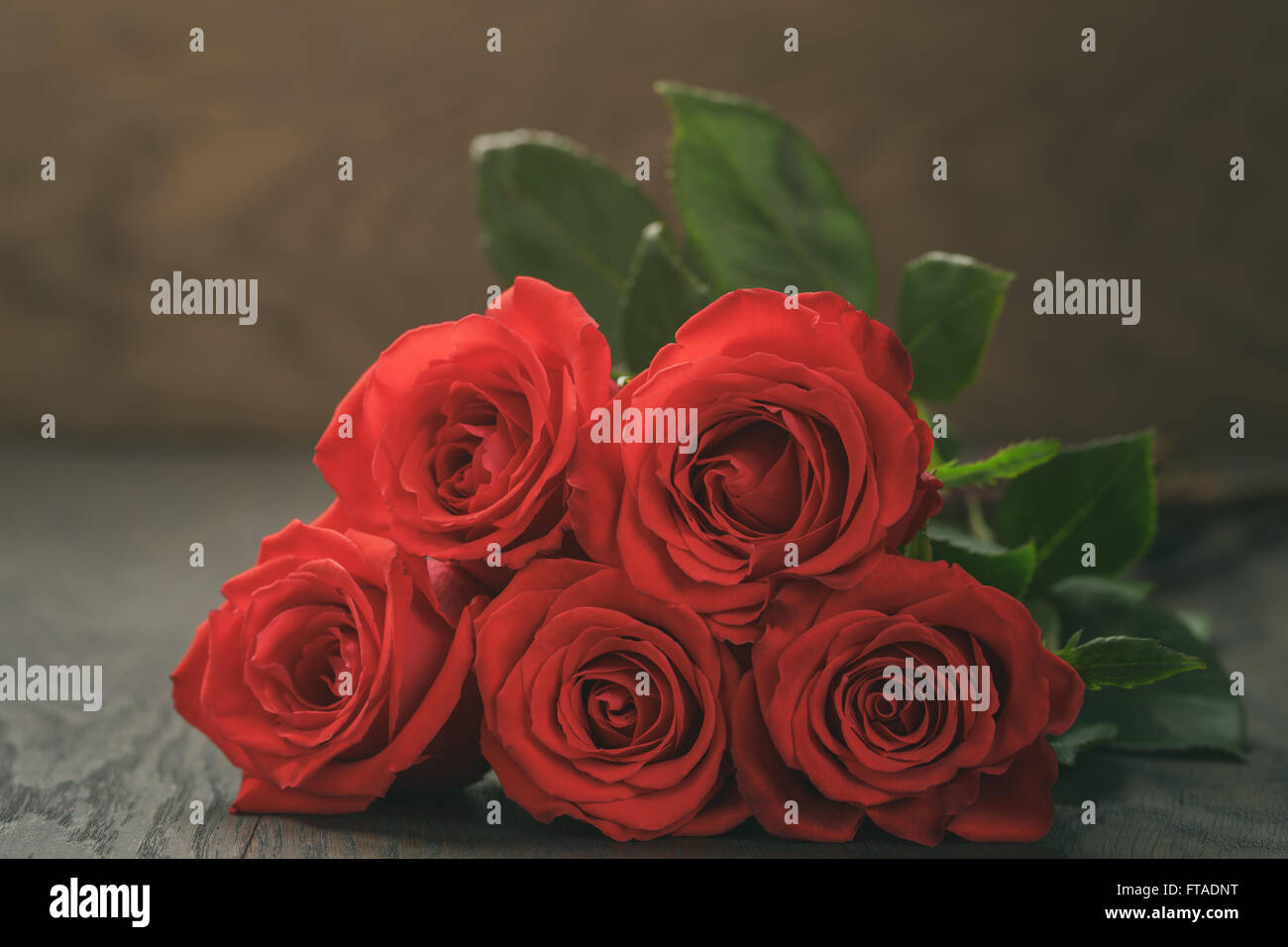 five red roses on wooden table Stock Photo - Alamy