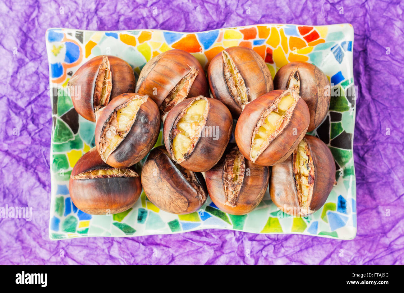 Top view of roasted chestnuts in their shells on a colorful mosaic ...