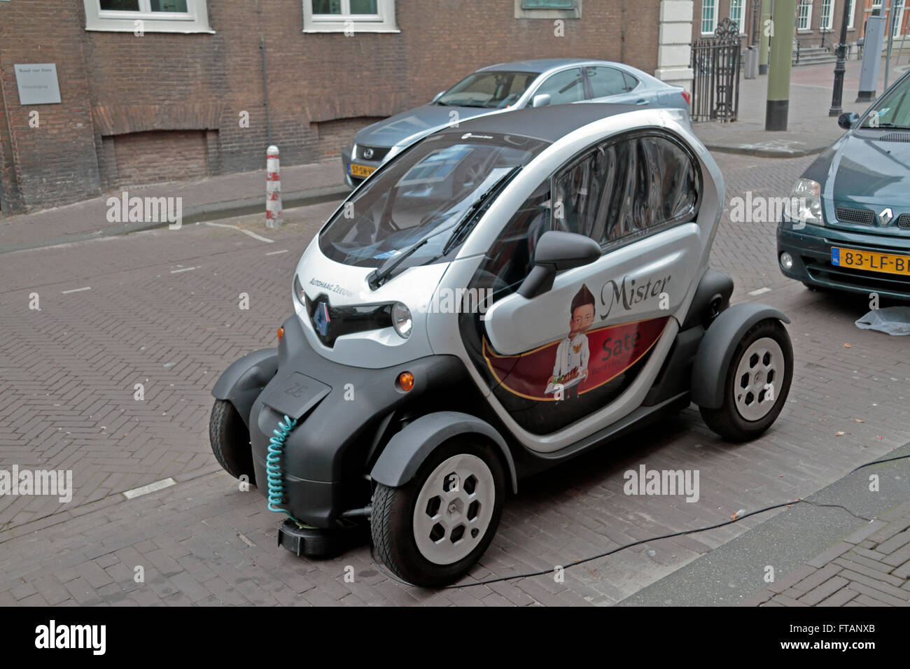 An electric powered Renault Twizy car plugged into a road side electric ...