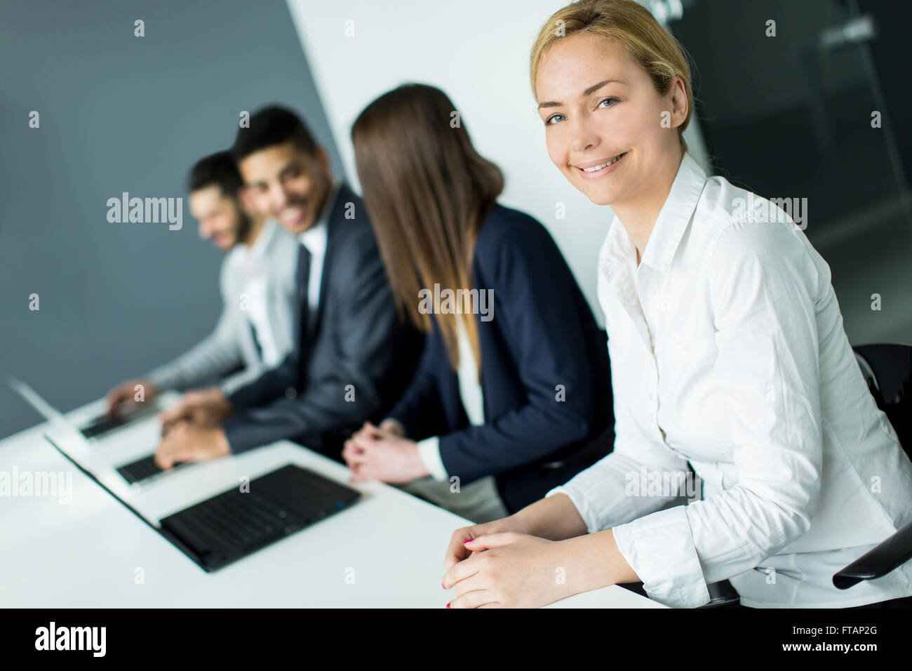 Businesswoman sitting with her colleagues in the office Stock Photo - Alamy