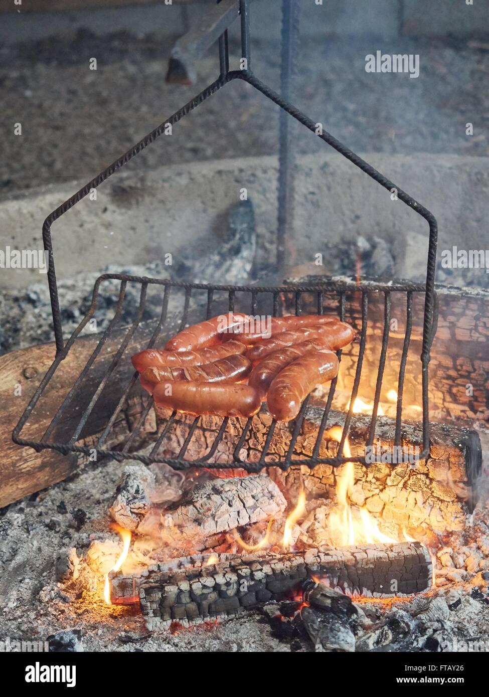 Sausages hanging above campfire in a barbecue hut. Smoke rising from ...