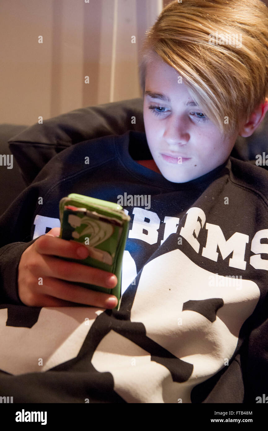 A teenage boy plays with his phone Stock Photo - Alamy