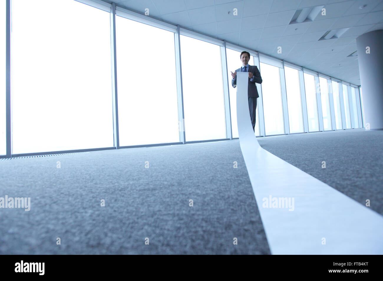 Office worker unrolling long sheet of paper Stock Photo - Alamy