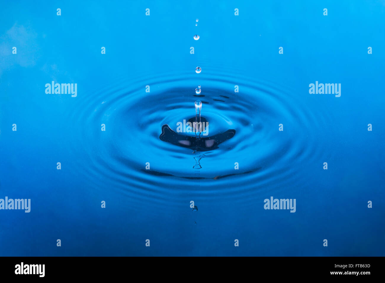 Falling drop of water in blue water, closeup Stock Photo - Alamy