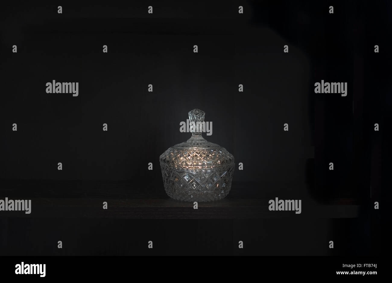 Crystal bowl with lid still life against dark background, chiaroscuro ...