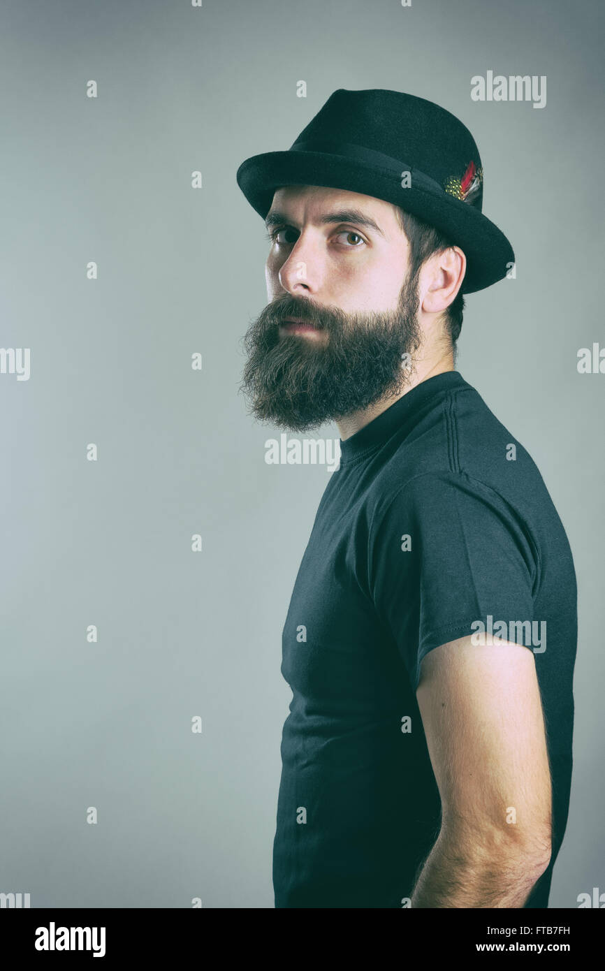 Side View Of Tough Bearded Macho Man Wearing Black T Shirt And Hat