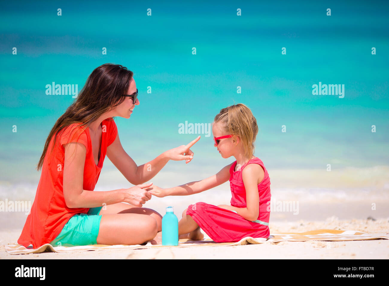 Mother Applying Sun Protection Cream To Her Daughter At Tropical Beach