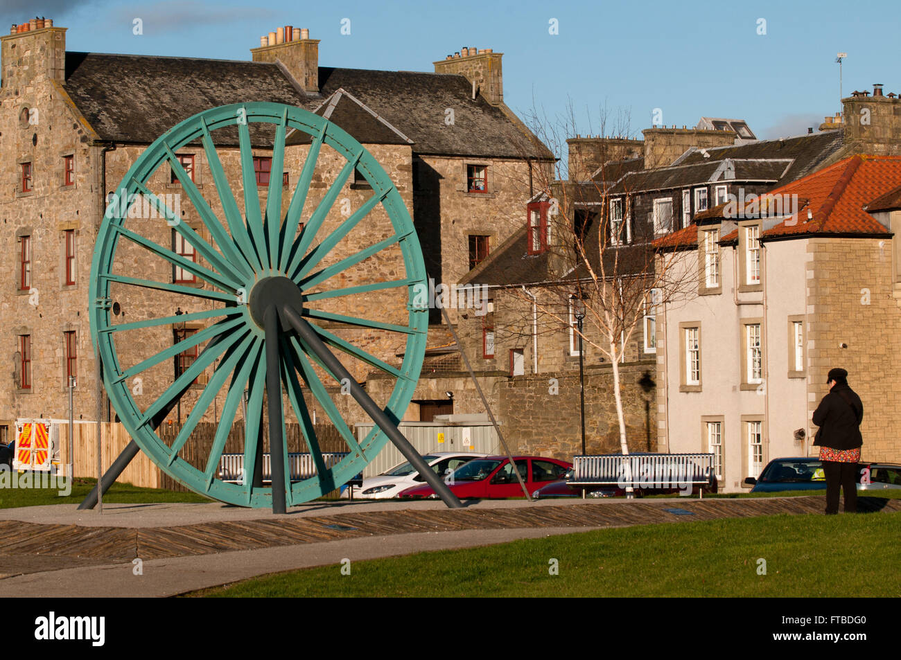 A person looks at a statue of a mining tower wheel in Bo'Ness in front ...
