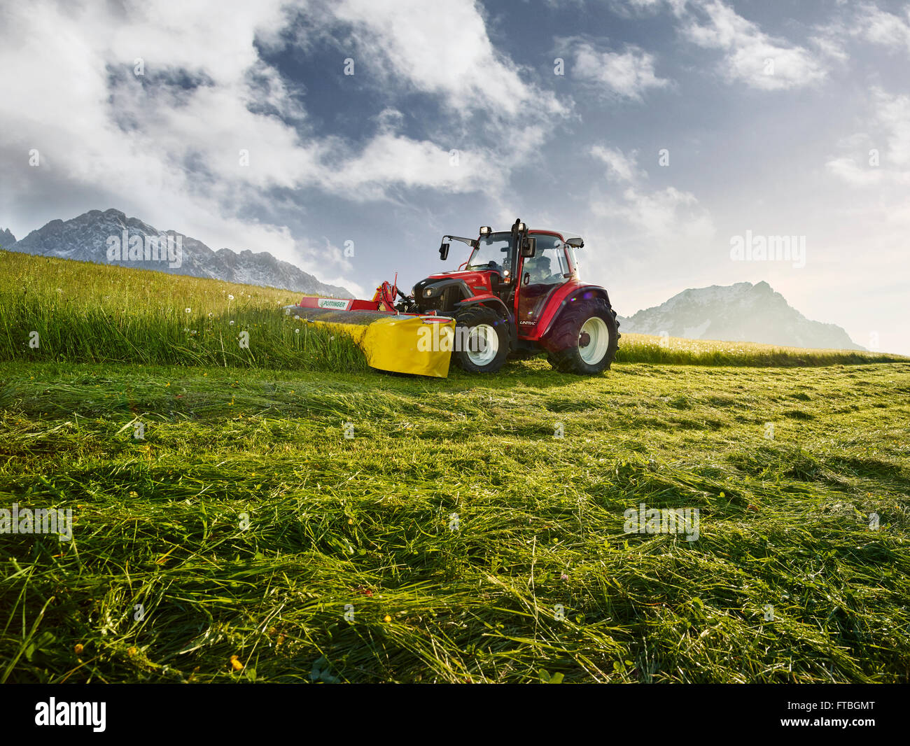 Tractor mowing a field at sunrise, Söll, Kaiser Mountains, Tyrol ...