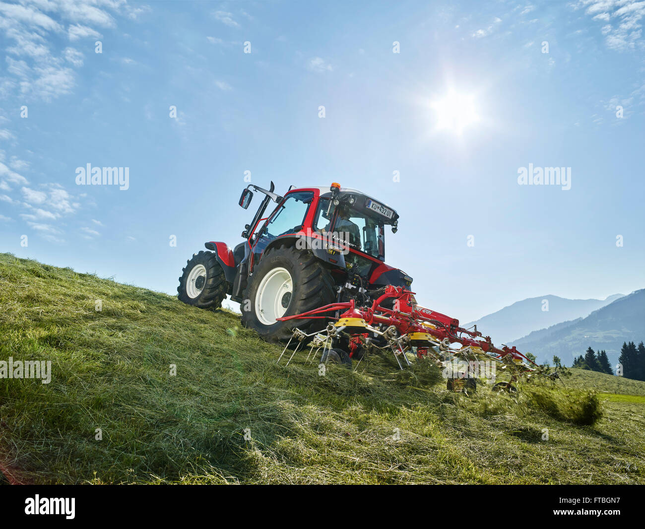 Tractor tedding the freshly cut hay with a tedder, Hopfgarten ...