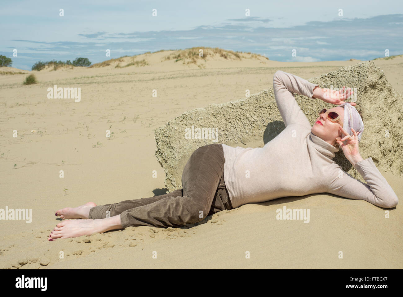 Woman lying on the sand near the stone Stock Photo - Alamy