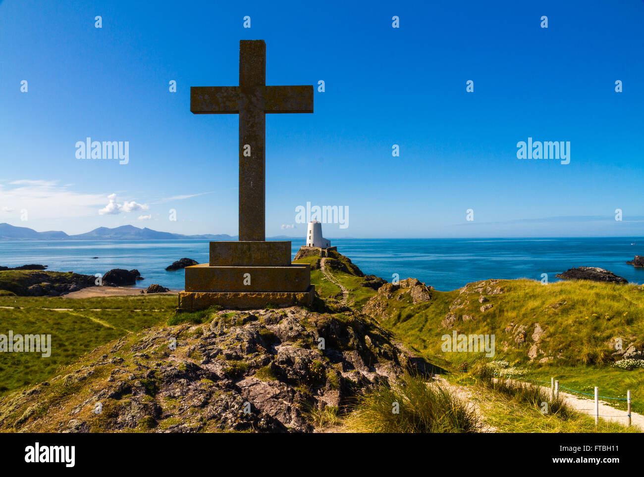 Religious cross with lighthouse in background. Llanddwyn Island, a ...
