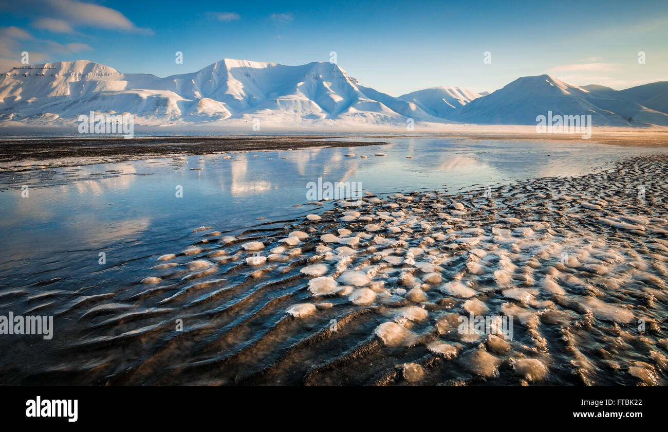 Sunrise ice formations on Sjøskrenten beach with views to Hiorthfjellet ...
