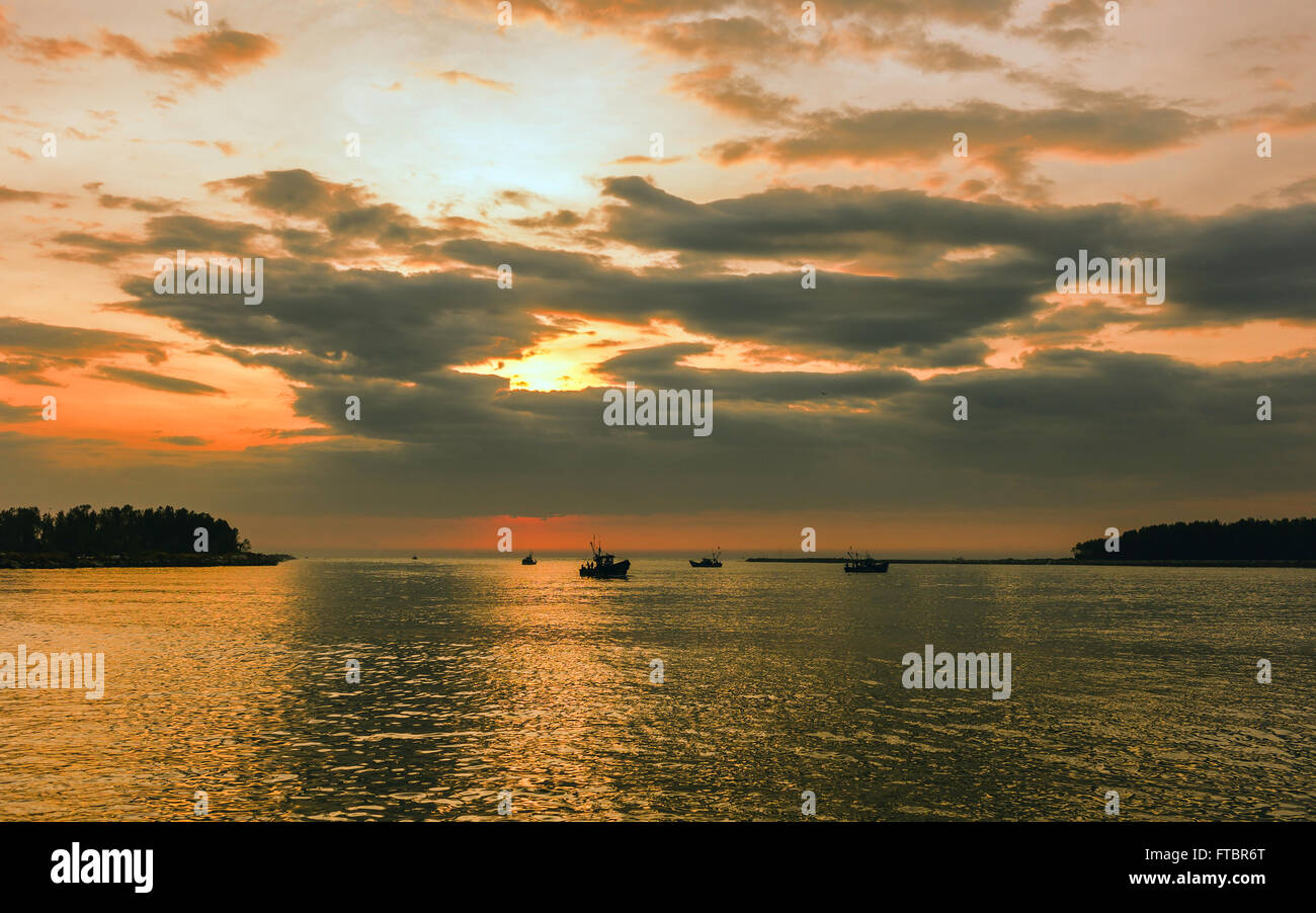 Small trawlers return home after a deep sea fishing excursion at dusk ...