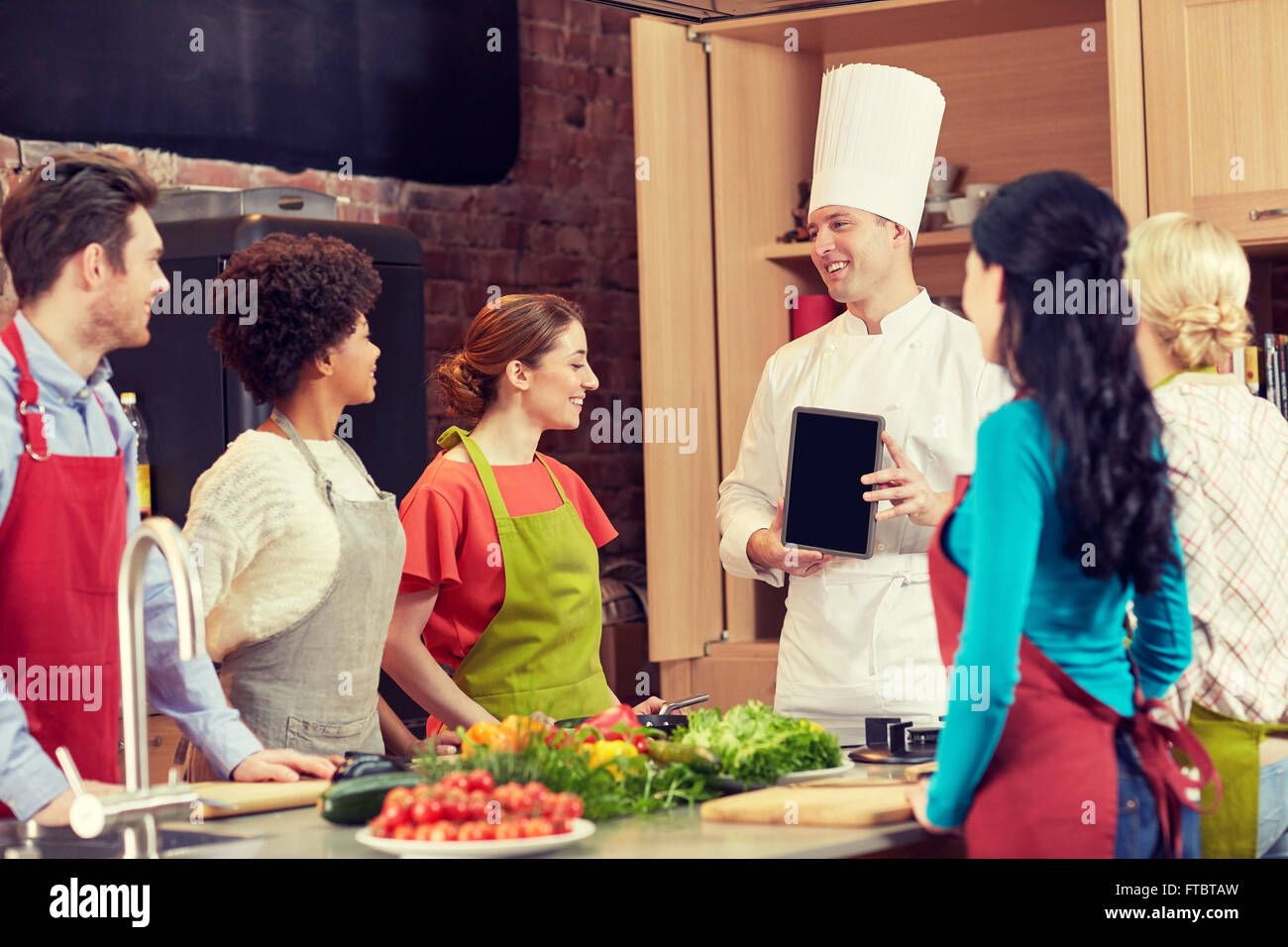 happy friends with chef and tablet pc in kitchen Stock Photo - Alamy